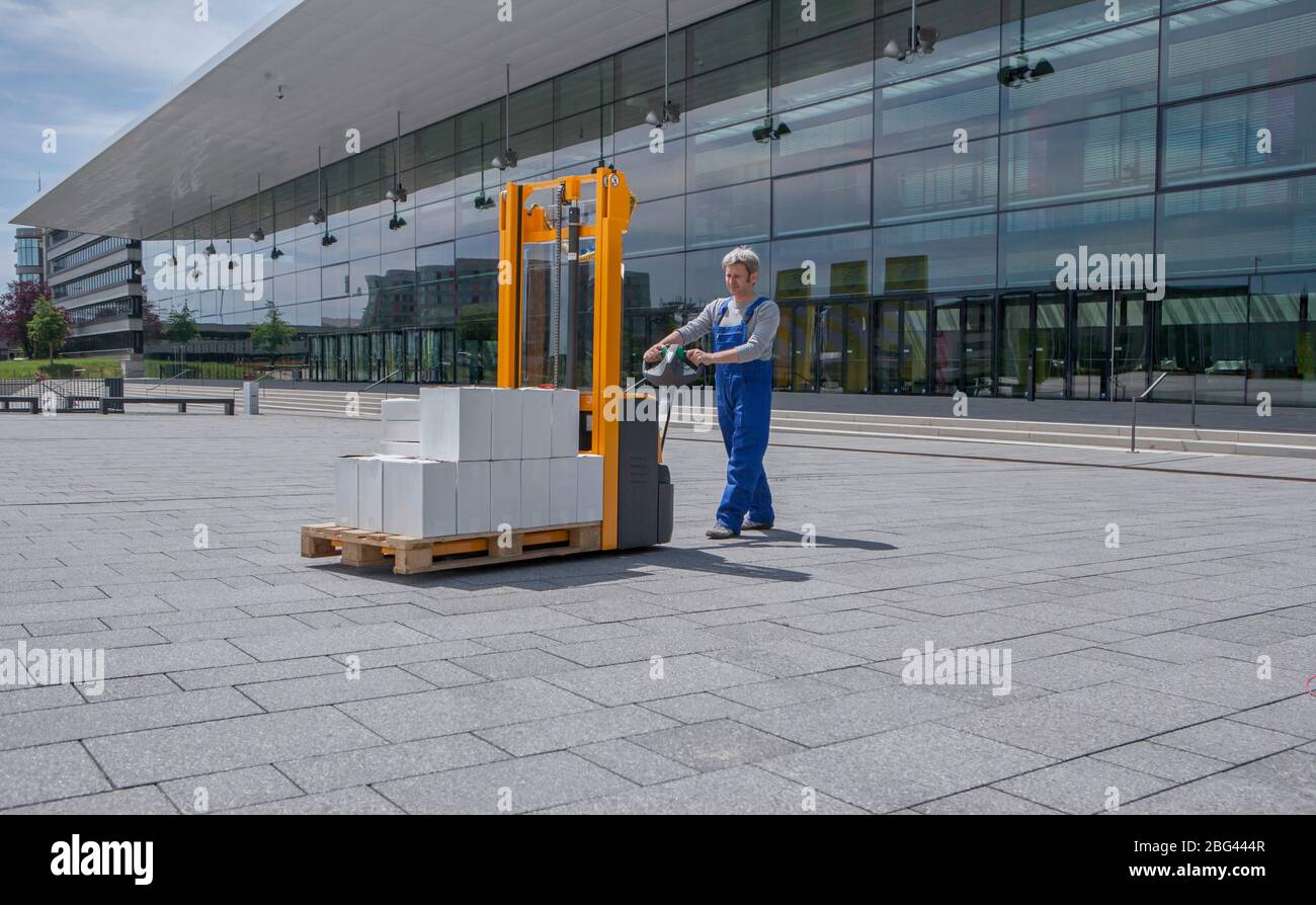 man in overalls operates an electric stacker loaded with boxes Stock ...