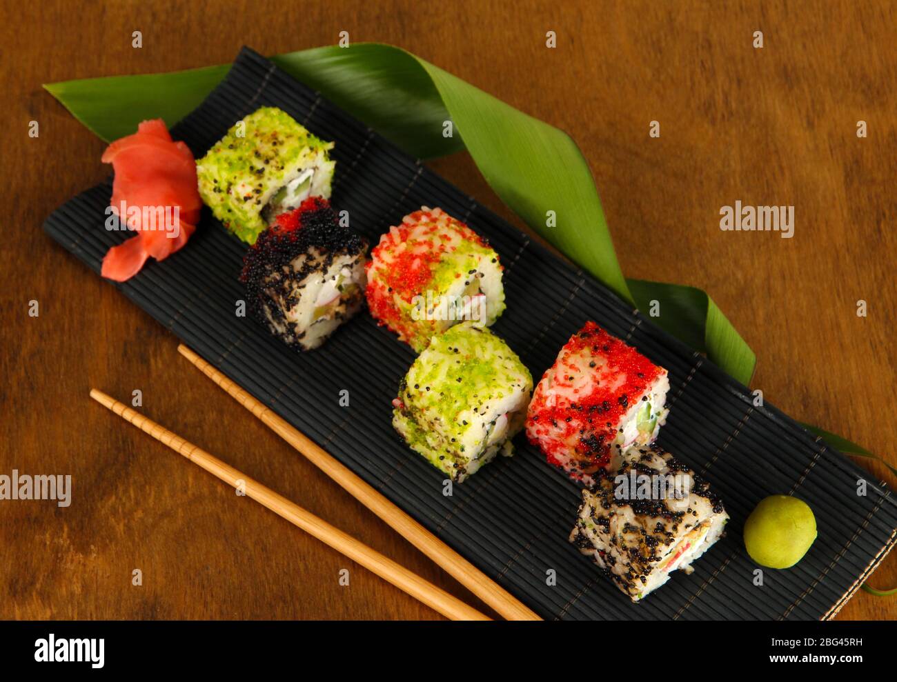 Tasty Maki sushi - Roll on mat on brown background Stock Photo - Alamy