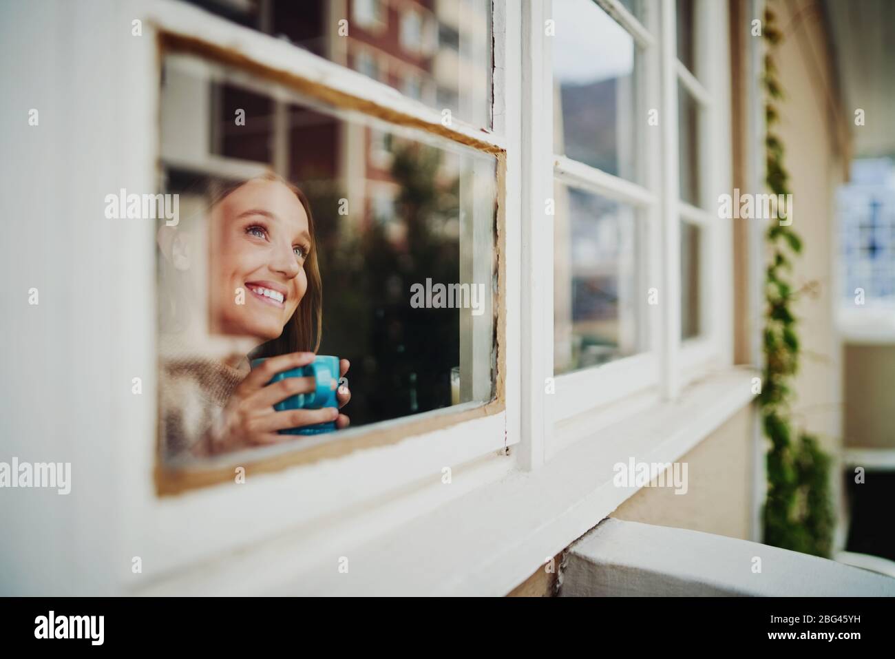 Beautiful young woman smiling drinking coffee and daydreaming enjoying ...