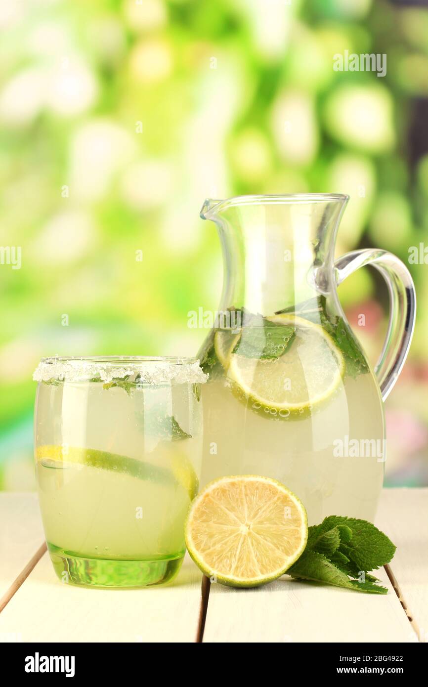 Citrus lemonade in pitcher and glass on wooden table on natural ...