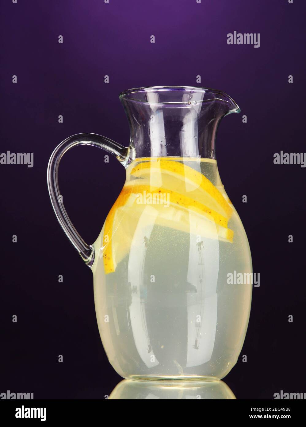 Lemonade in pitcher on purple background Stock Photo - Alamy