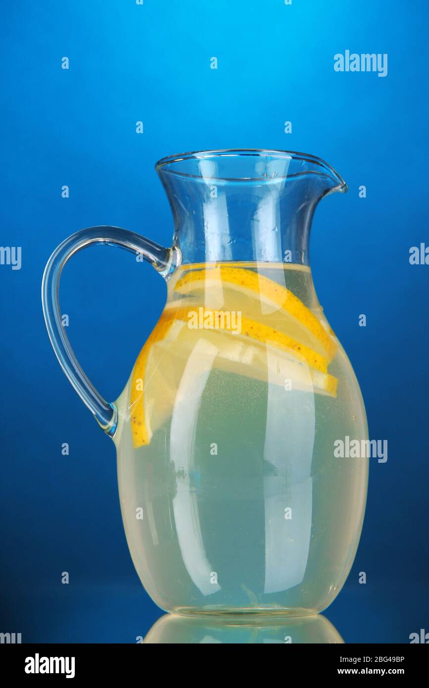 Lemonade in pitcher on blue background Stock Photo - Alamy