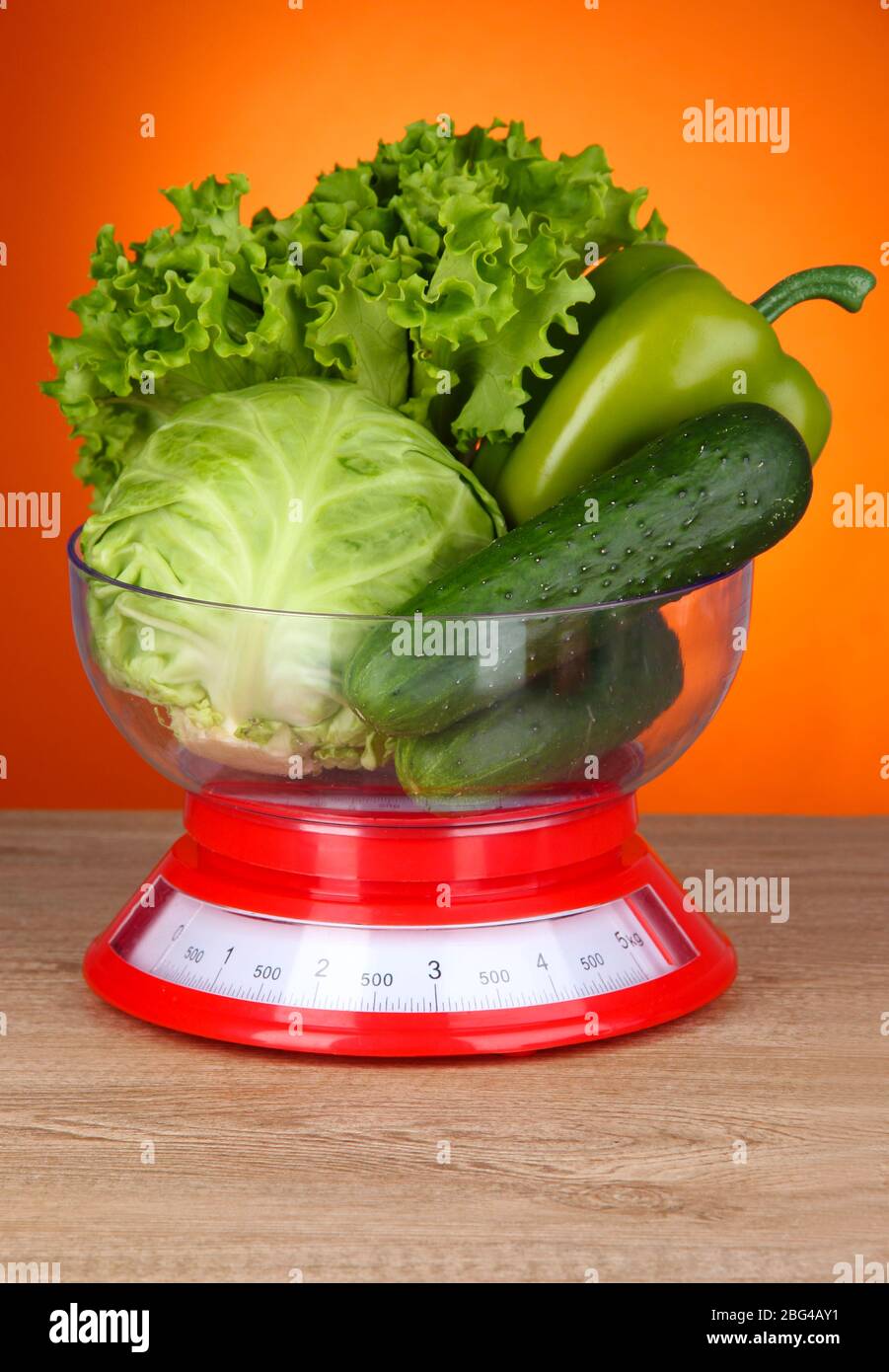 Fresh vegetables in scales on table on orange background Stock Photo ...