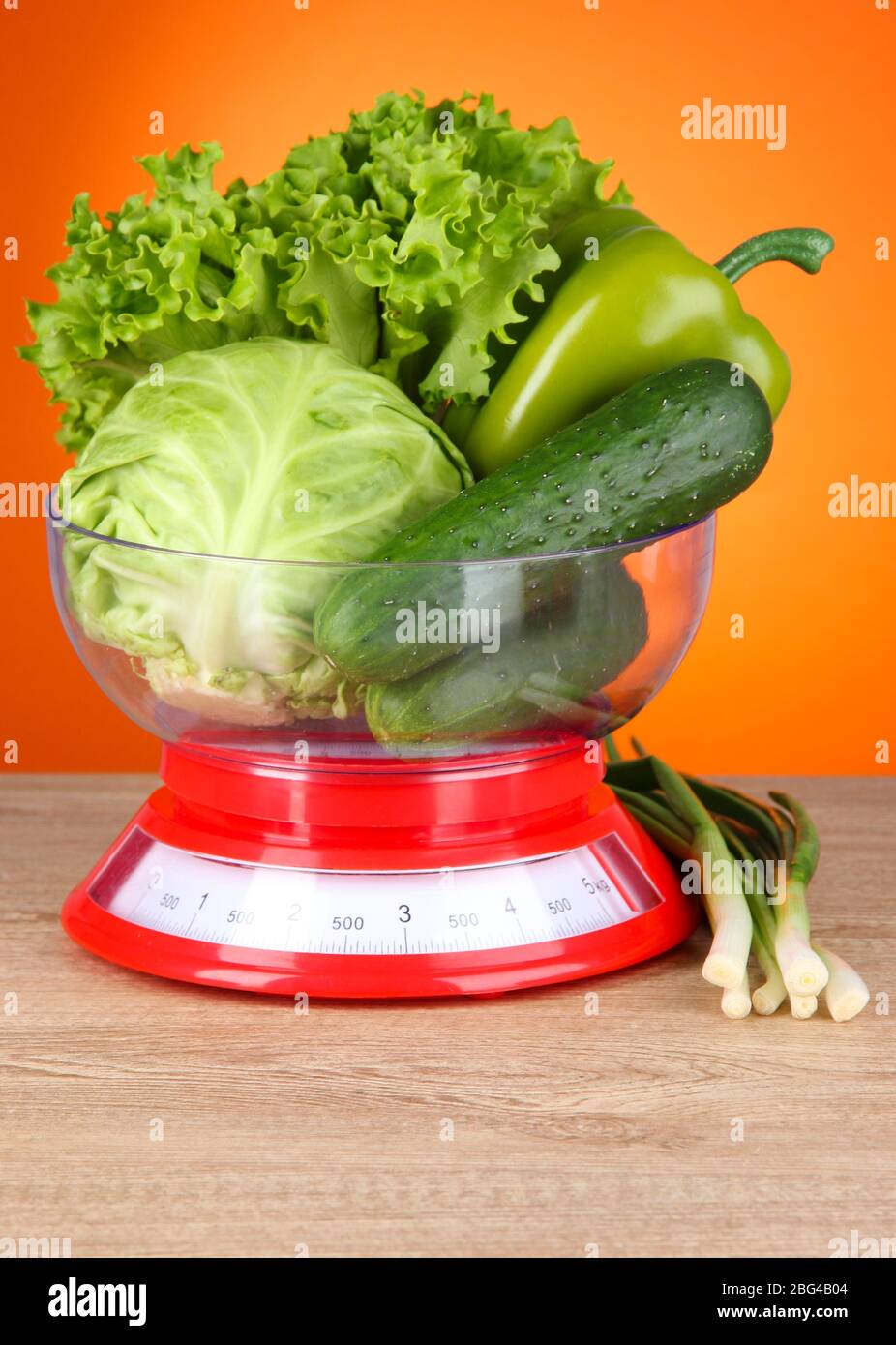 Fresh vegetables in scales on table on orange background Stock Photo ...