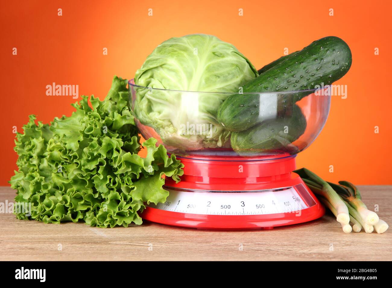 Fresh vegetables in scales on table on orange background Stock Photo ...