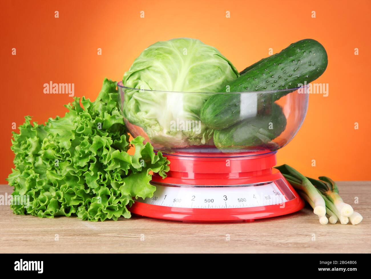 Fresh vegetables in scales on table on orange background Stock Photo ...