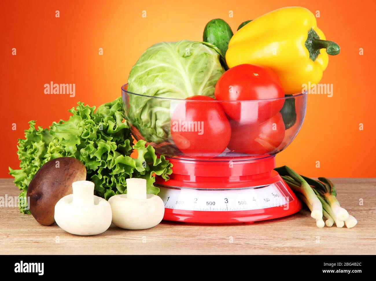 Fresh vegetables in scales on table on orange background Stock Photo ...
