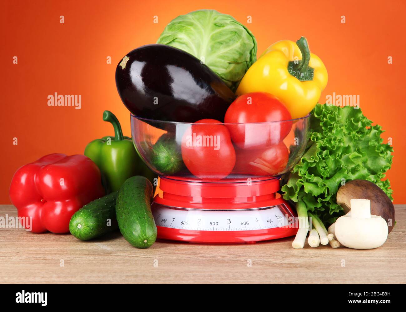 Fresh vegetables in scales on table on orange background Stock Photo ...