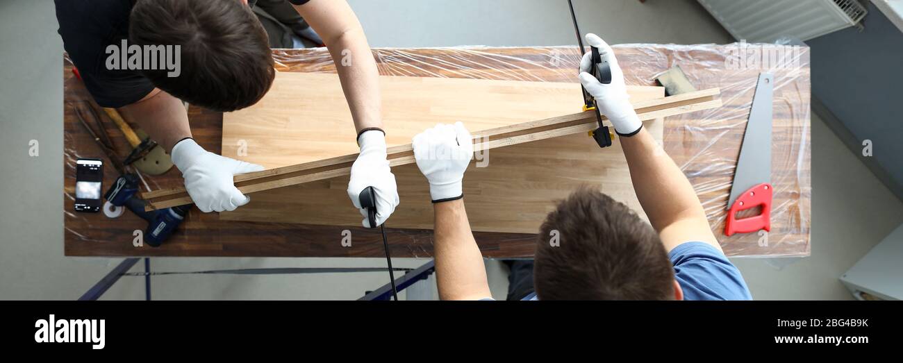 Men measure thickness of wood material Stock Photo - Alamy