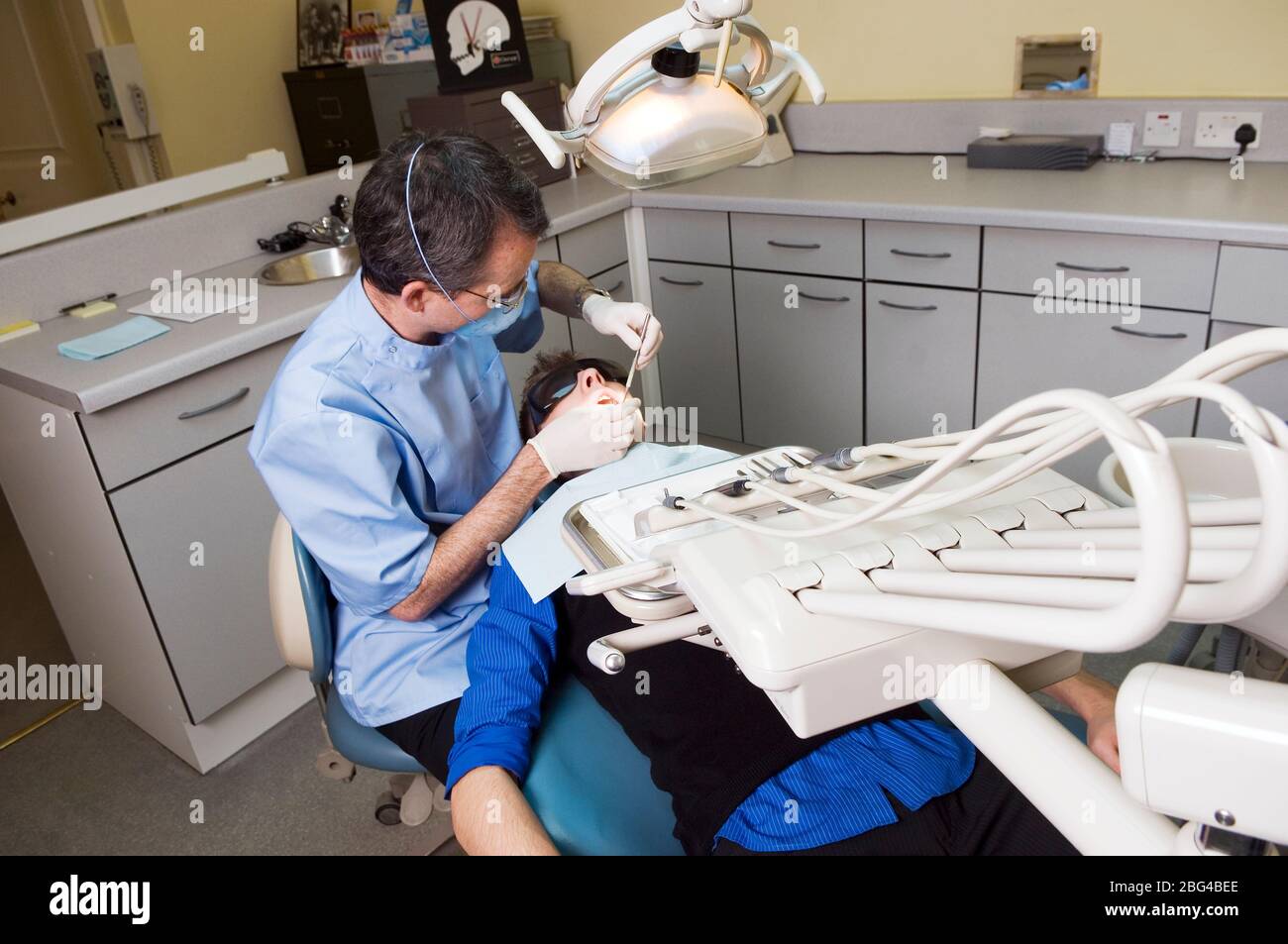 Dentist wearing safety glasses and mouth mask examines the teeth of ...