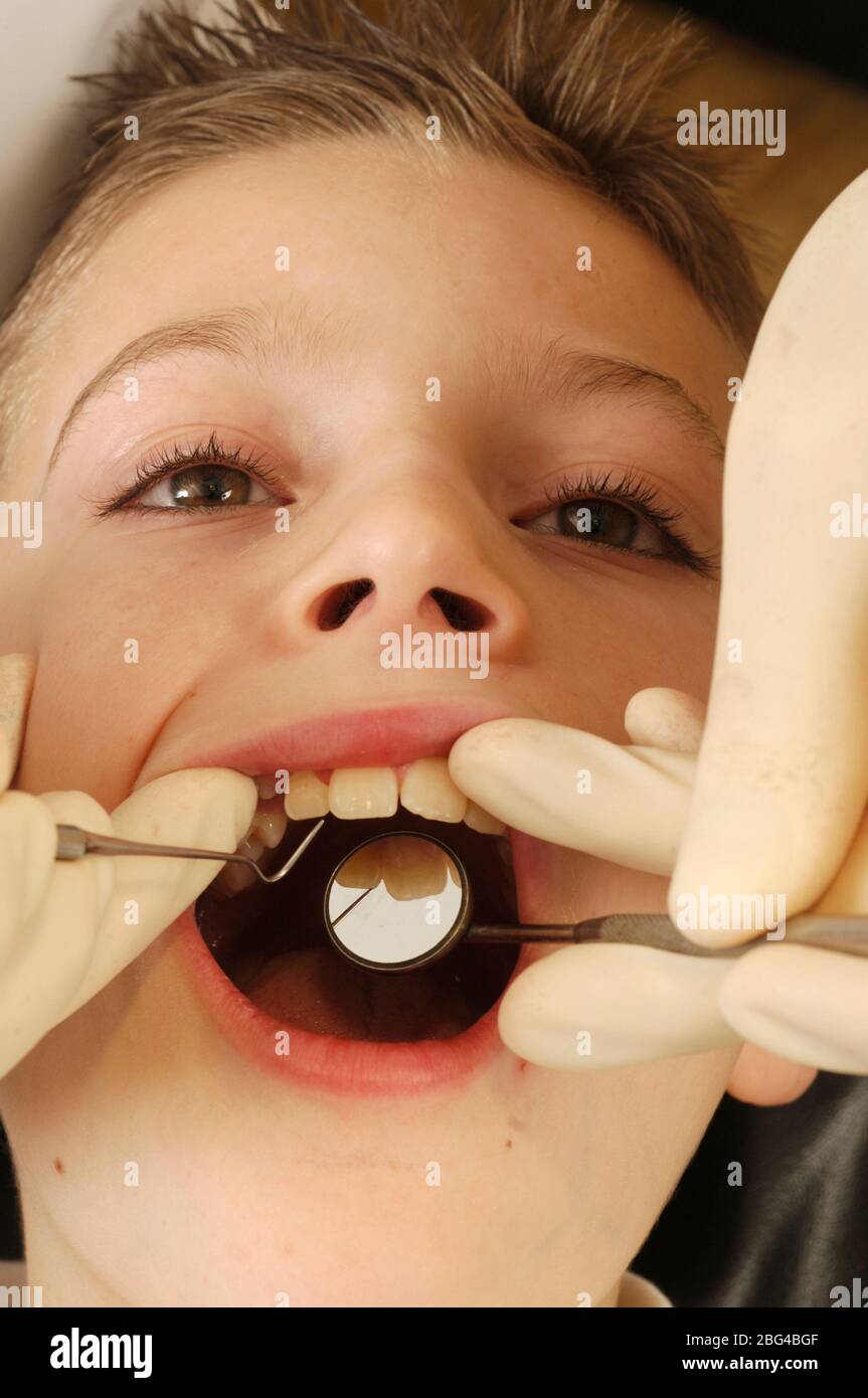 A dentist uses a dental pick and dental mirror to examine the condition ...