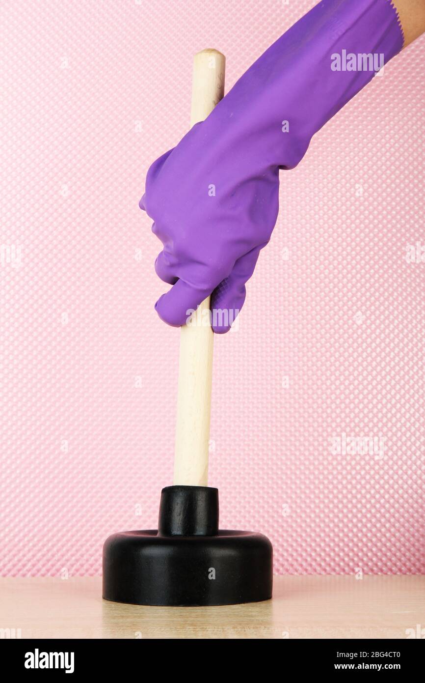 Toilet plunger in hand on pink background Stock Photo - Alamy