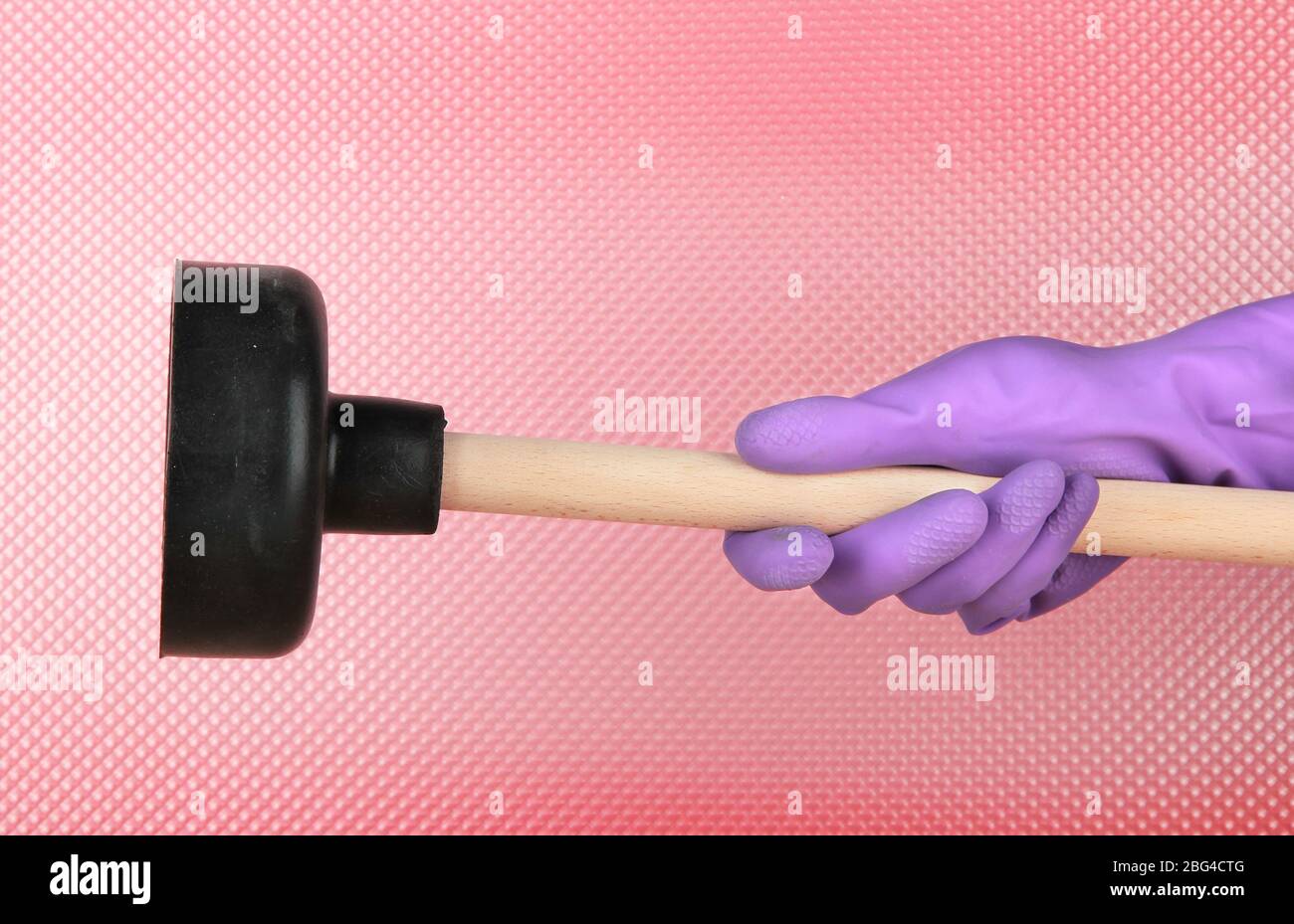 Toilet plunger in hand on pink background Stock Photo - Alamy
