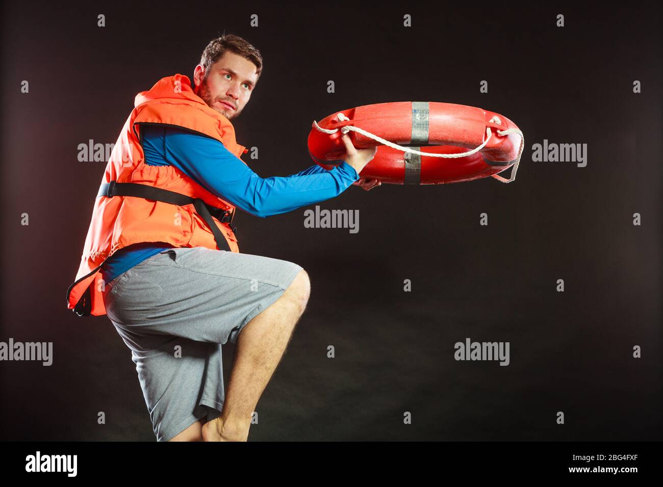 Lifeguard in life vest jacket throwing ring buoy lifebuoy. Man ...