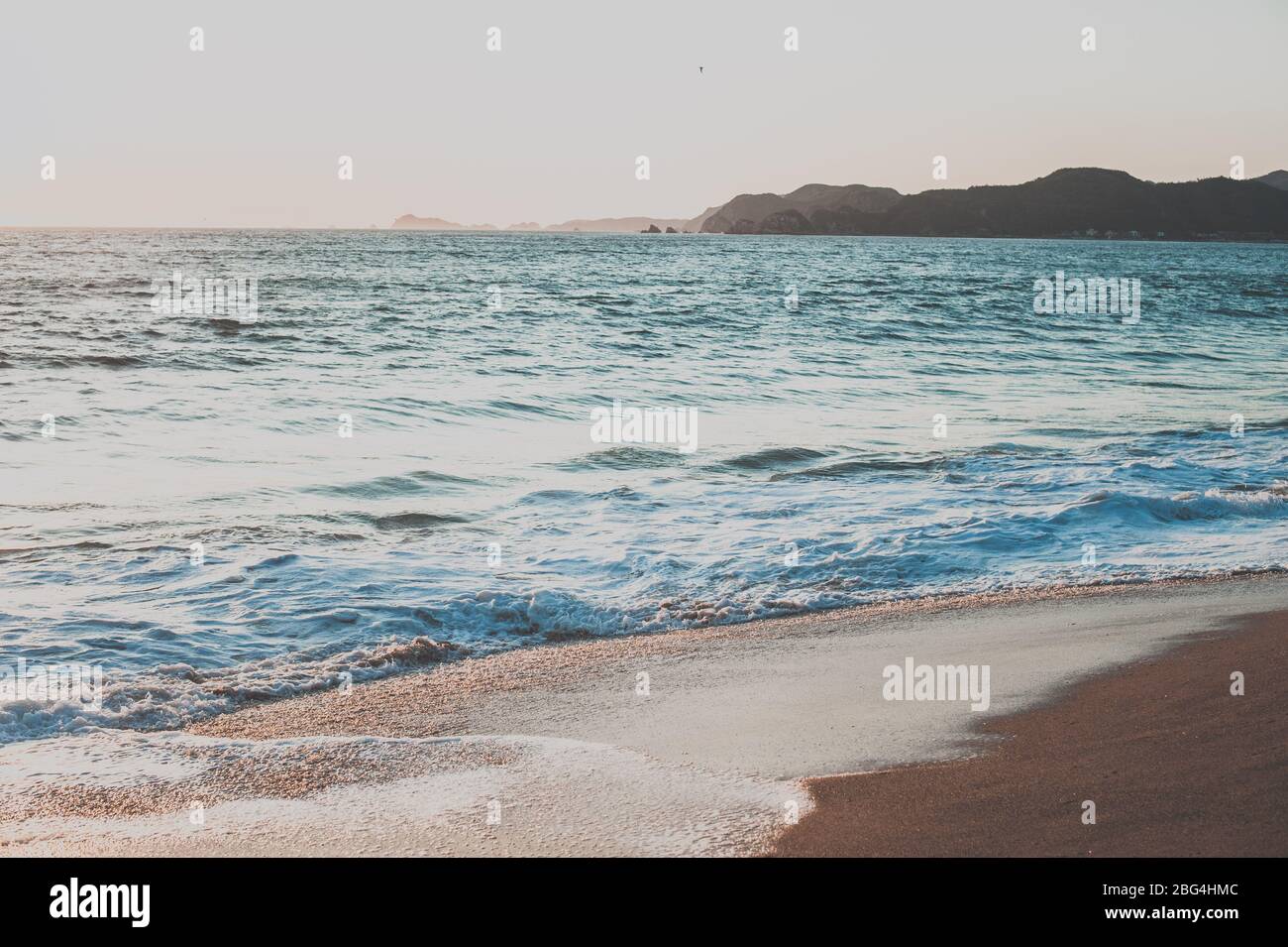 Tide going out on beach in Mexico at sunset with mountains behind Stock ...