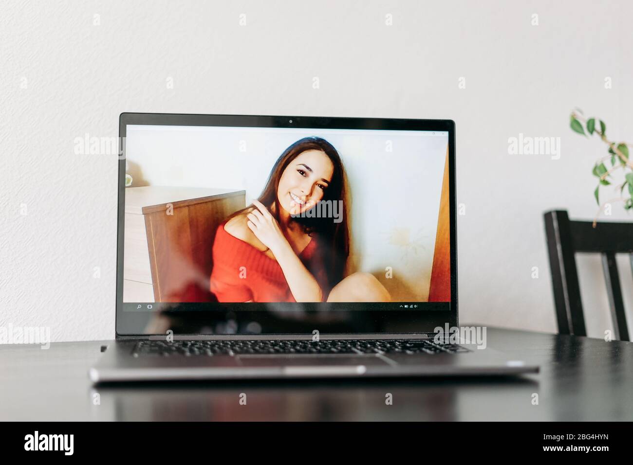 Open laptop on table with photo of laughing Asian girl in red dress ...