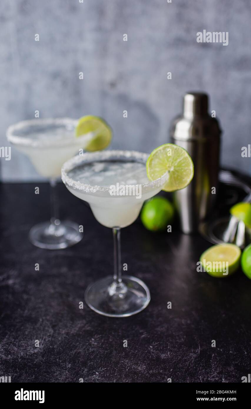 Two margarita cocktails with limes and shaker on black counter Stock ...