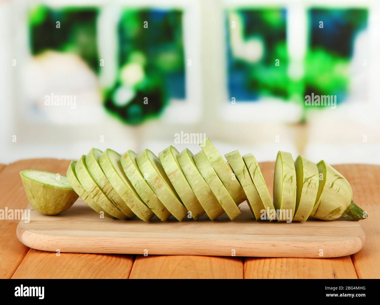 Fresh marrows on cutting board, on wooden table, on bright background ...