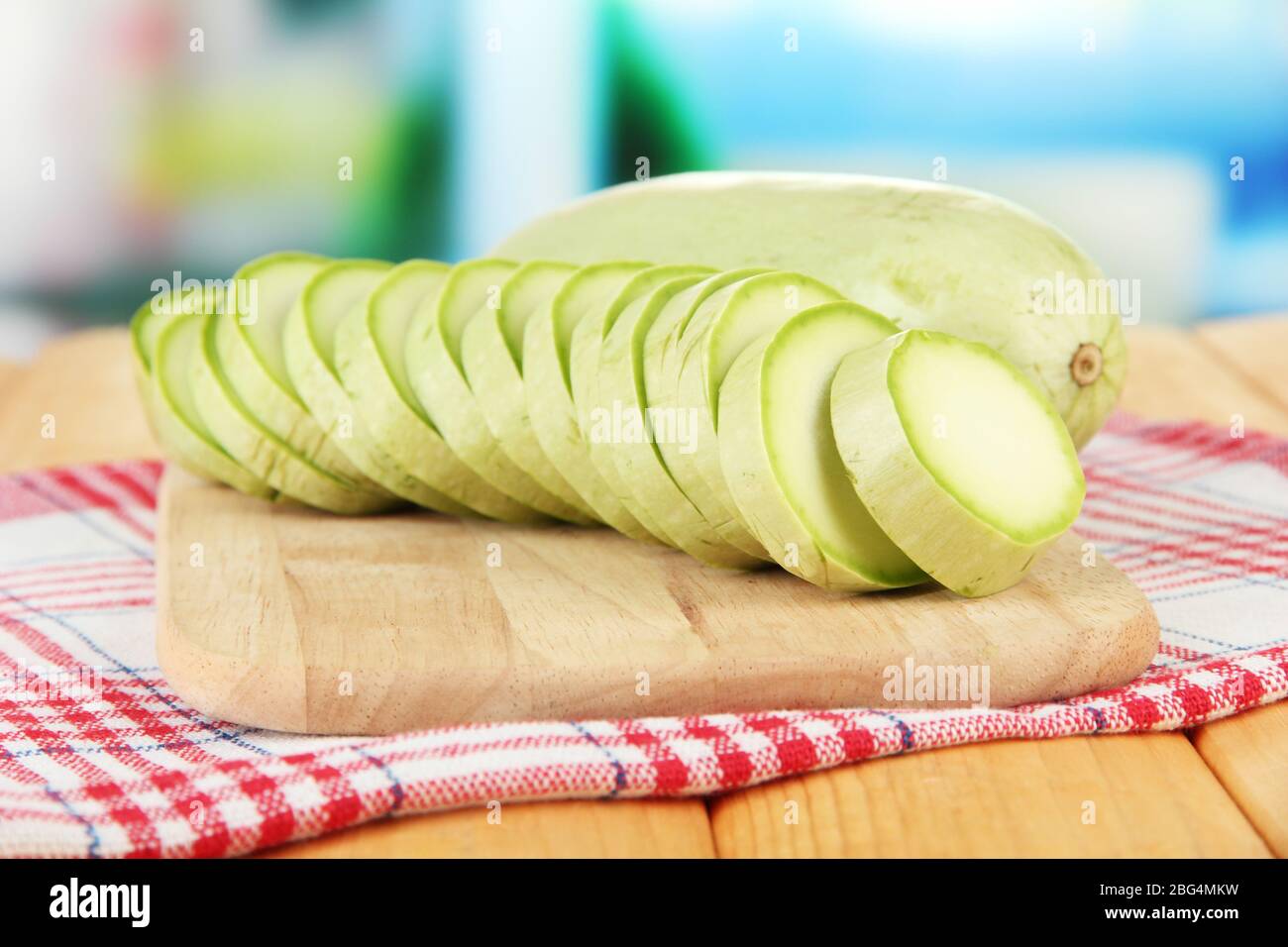 Fresh marrows on cutting board, on wooden table, on bright background ...