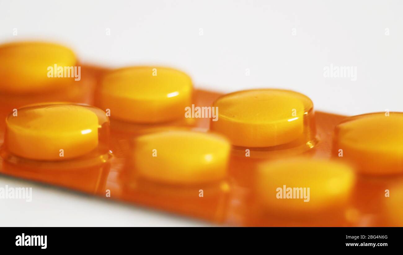 Close up shot of unused table of yellow round pills. Drugs, supplements ...