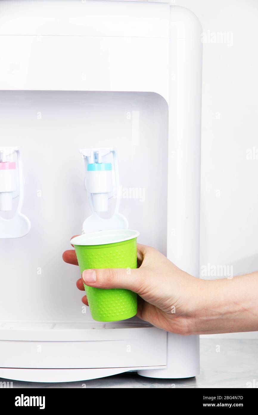 Woman filling cup at water cooler Stock Photo - Alamy