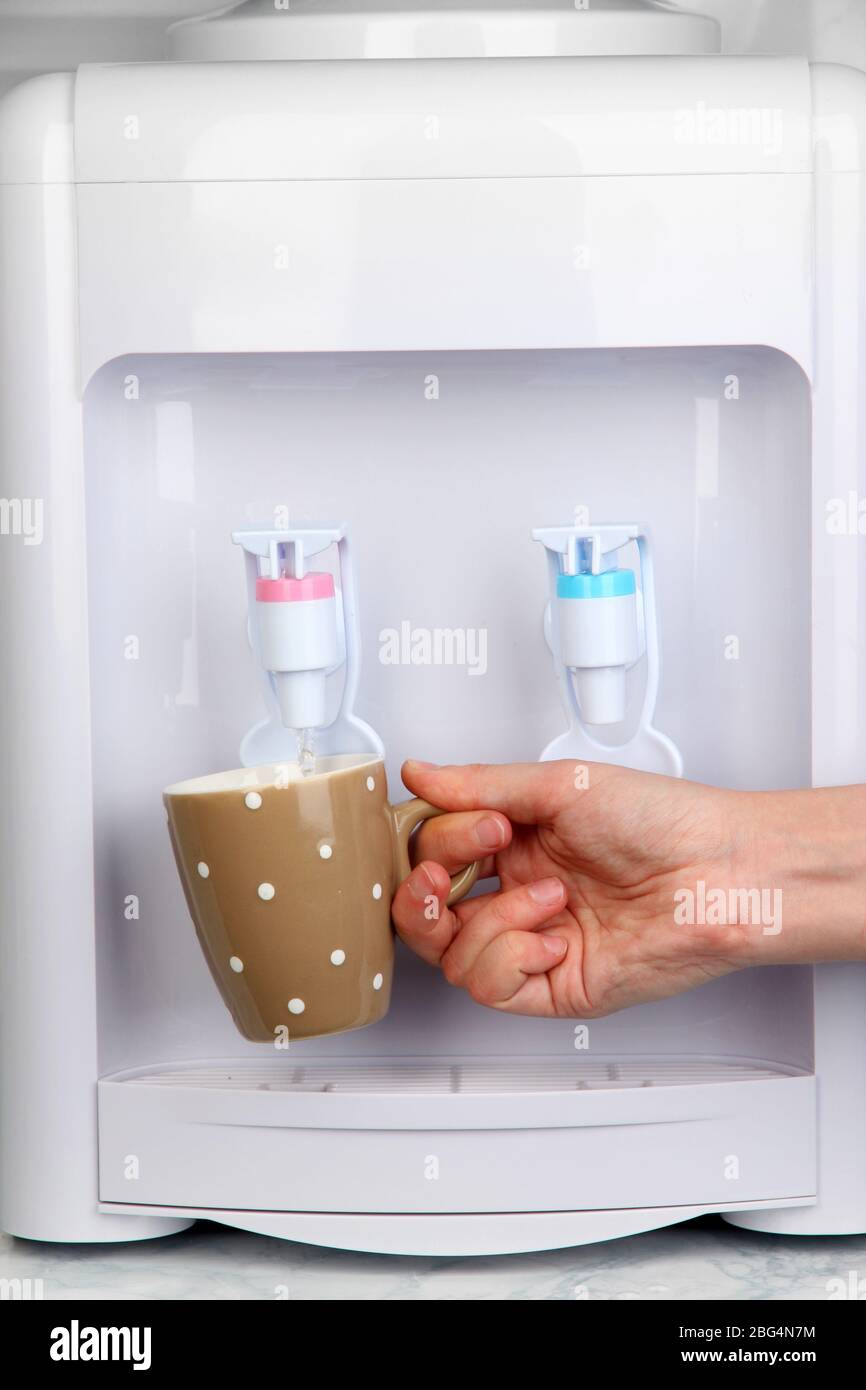 Woman filling cup at water cooler Stock Photo - Alamy