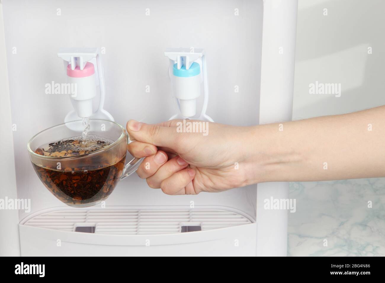 Woman filling cup at water cooler Stock Photo - Alamy