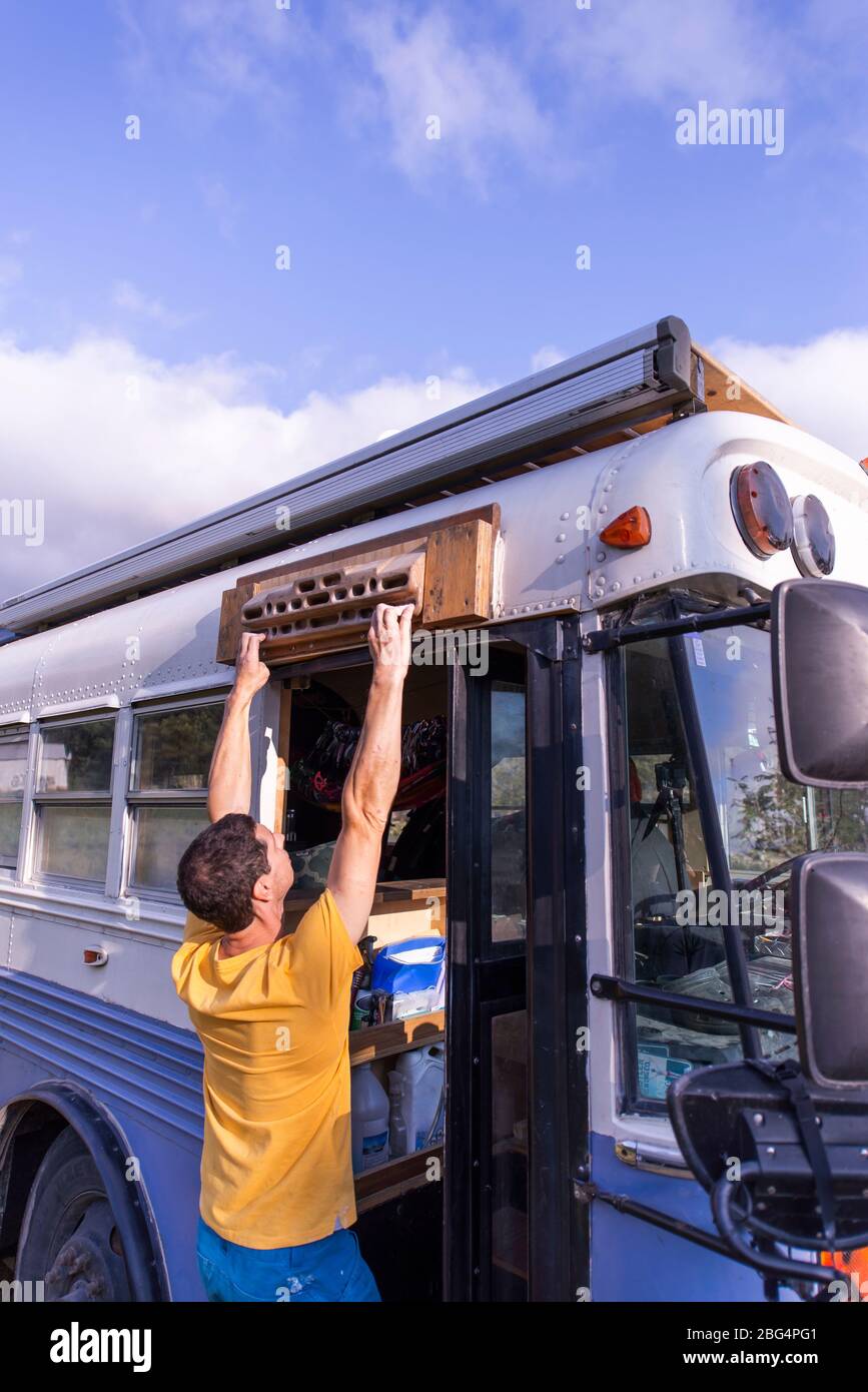 Climber hangboarding on a converted school bus in front of door Stock ...