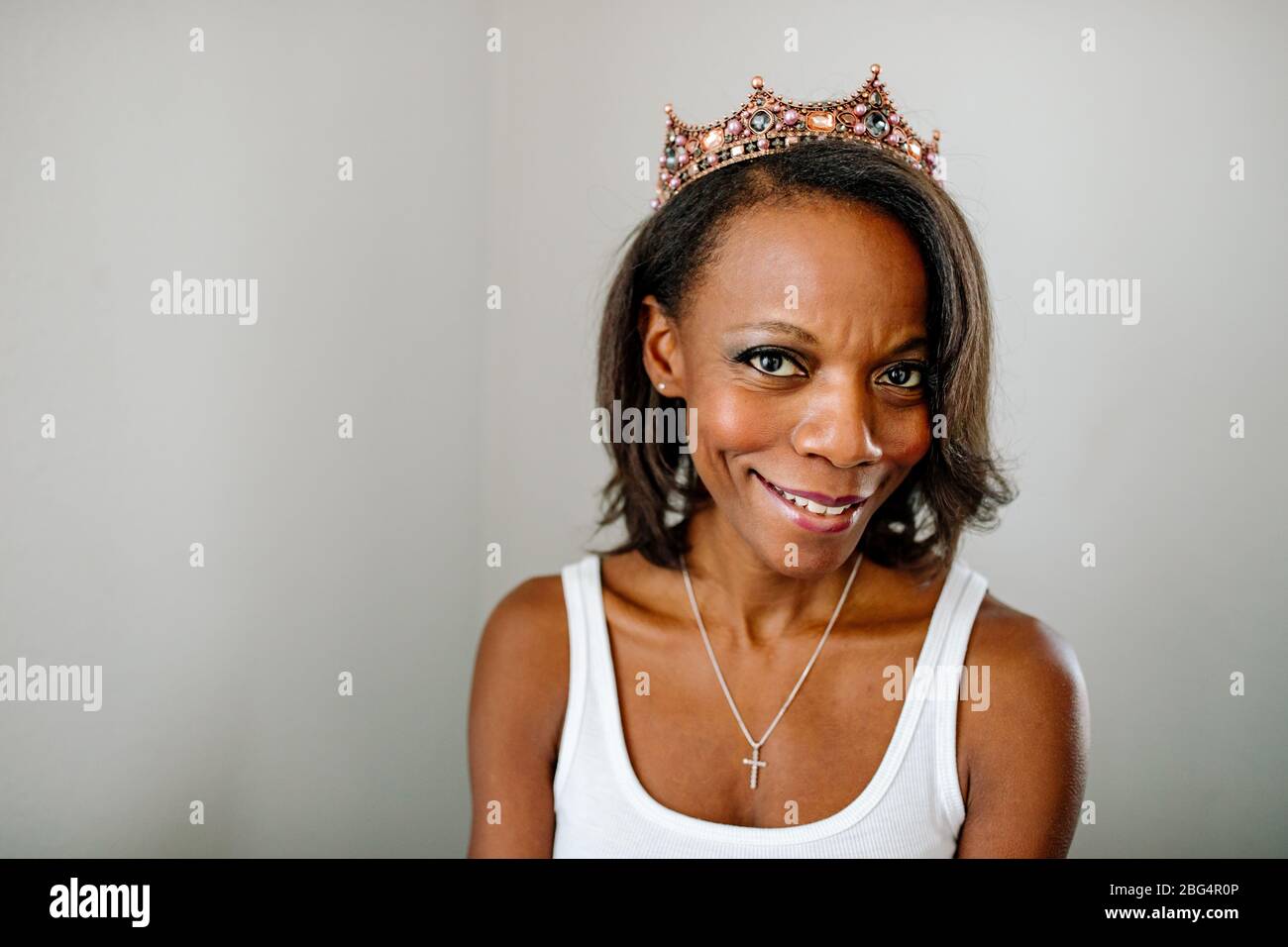 Smiling Black woman wearing tiara, tank top and cross necklace Stock ...