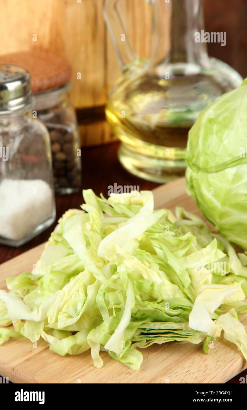 Green cabbage, oil, spices on cutting board, on wooden background Stock ...