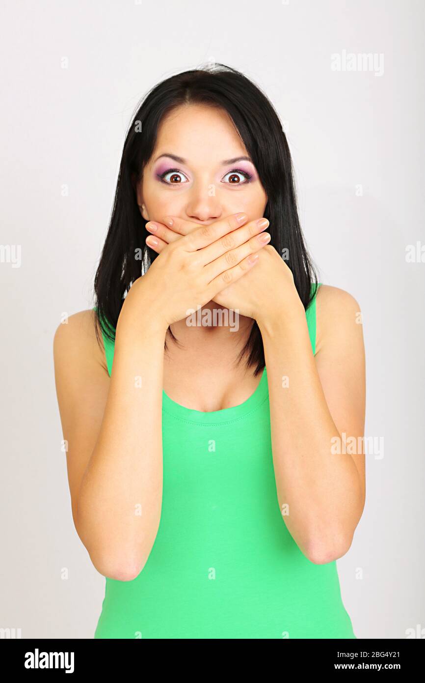 Girl shows sign of silence on grey background Stock Photo - Alamy