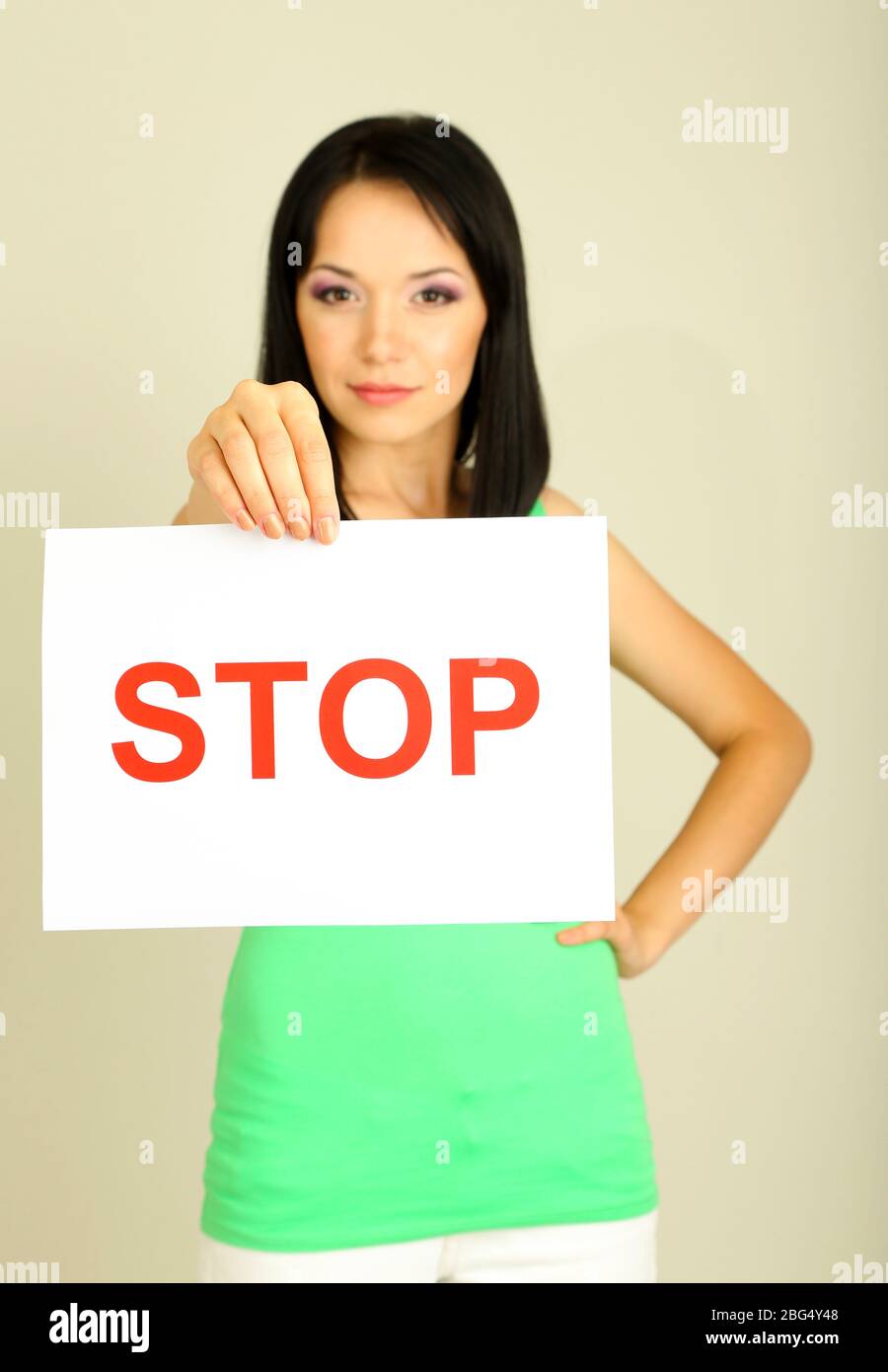 Girl showing stop sign on grey background Stock Photo - Alamy