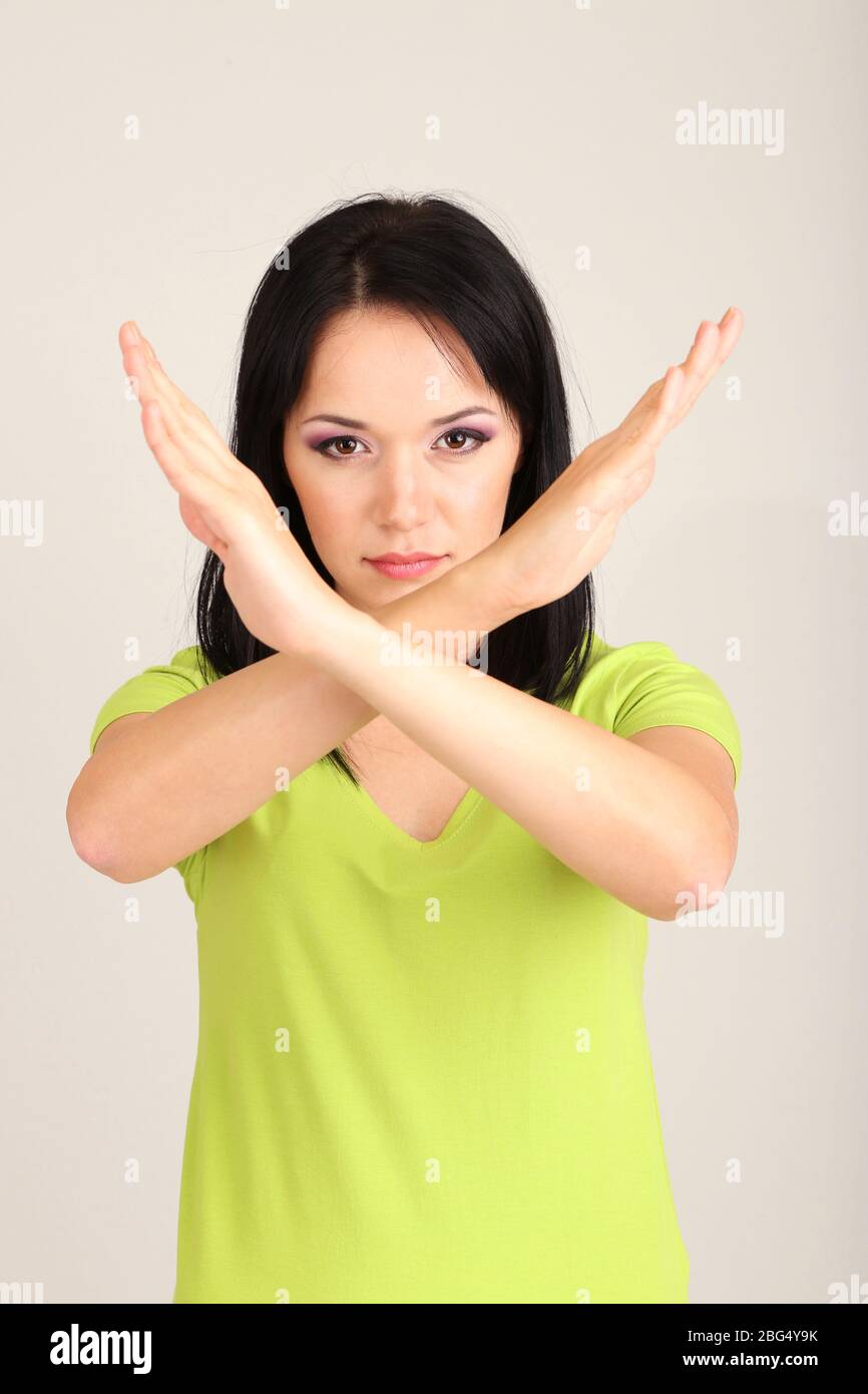 Girl showing stop sign on grey background Stock Photo - Alamy
