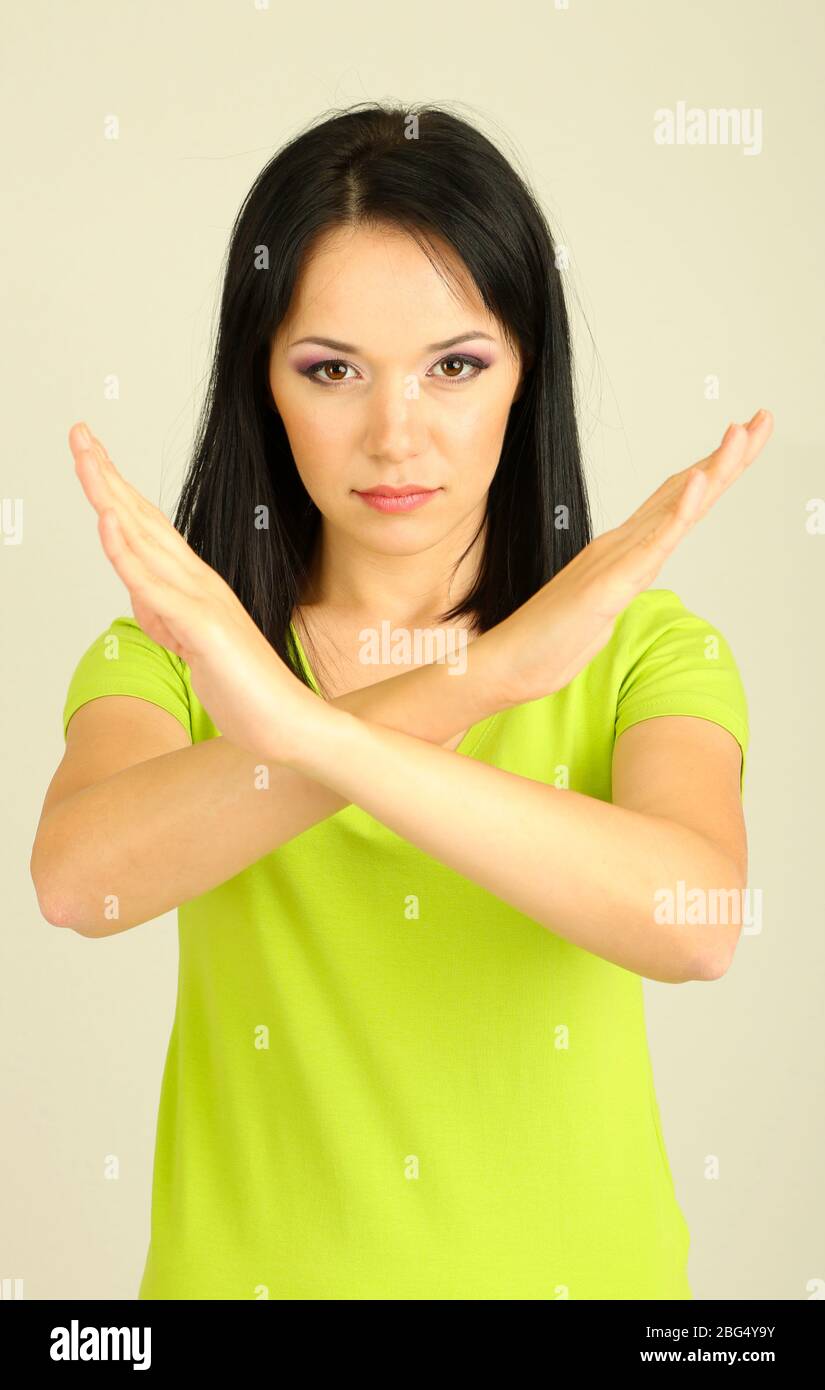 Girl showing stop sign on grey background Stock Photo - Alamy