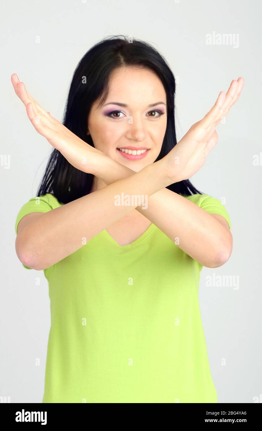 Girl showing stop sign on grey background Stock Photo - Alamy