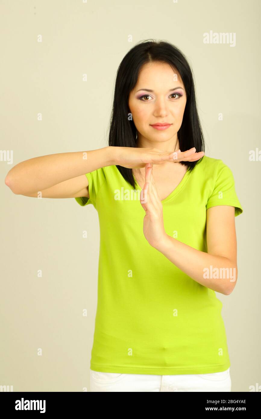 Girl showing time out sign on grey background Stock Photo - Alamy