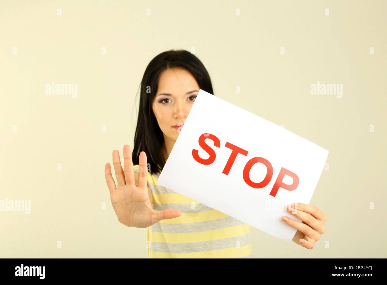 Girl showing stop sign on grey background Stock Photo - Alamy