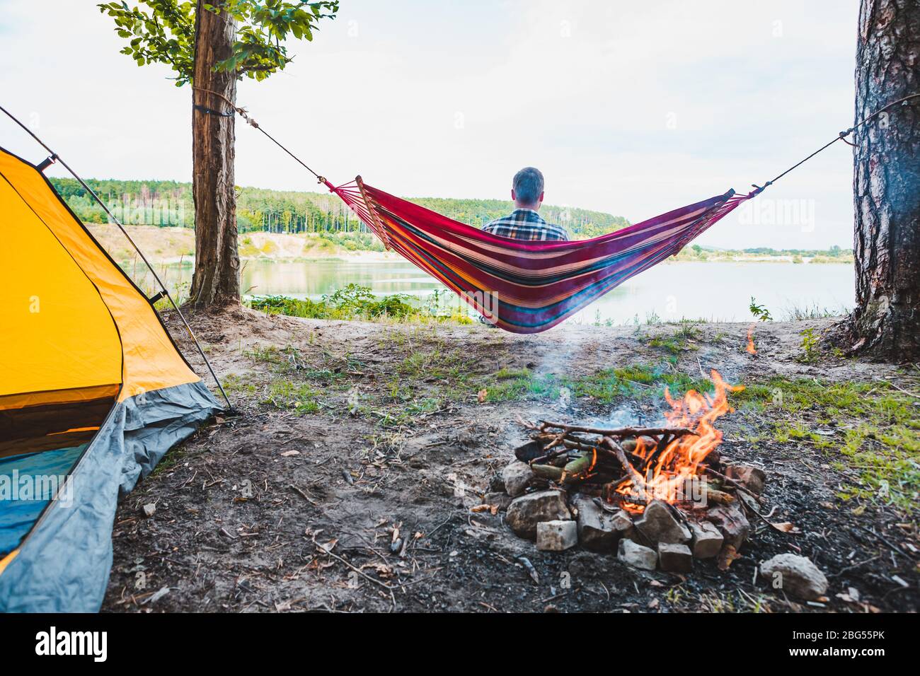 man laying on hammock at lake beach near camp fire Stock Photo - Alamy