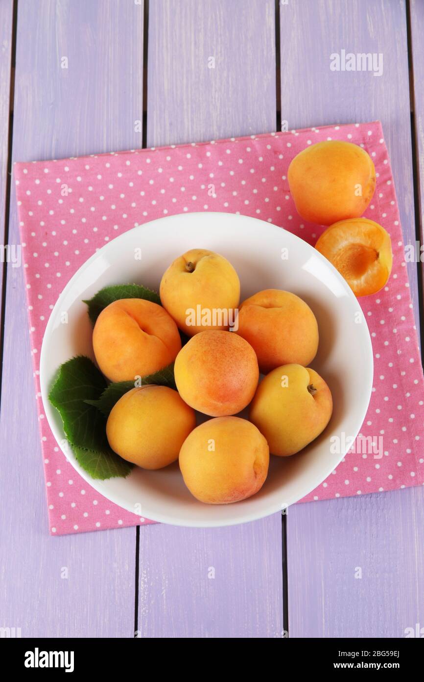 Apricots in plate on napkin on wooden table Stock Photo - Alamy