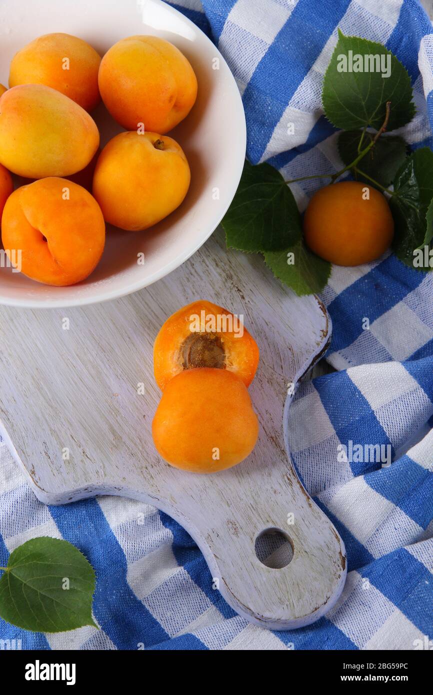 Apricots on board for cutting on napkin on wooden table Stock Photo - Alamy