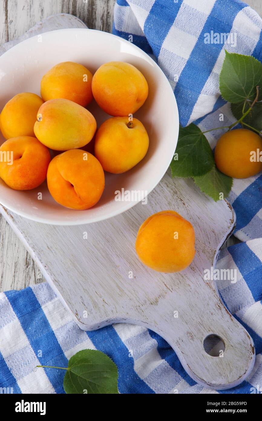 Apricots on board for cutting on napkin on wooden table Stock Photo - Alamy