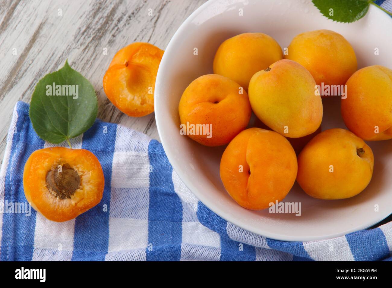 Apricots on board for cutting on napkin on wooden table Stock Photo - Alamy
