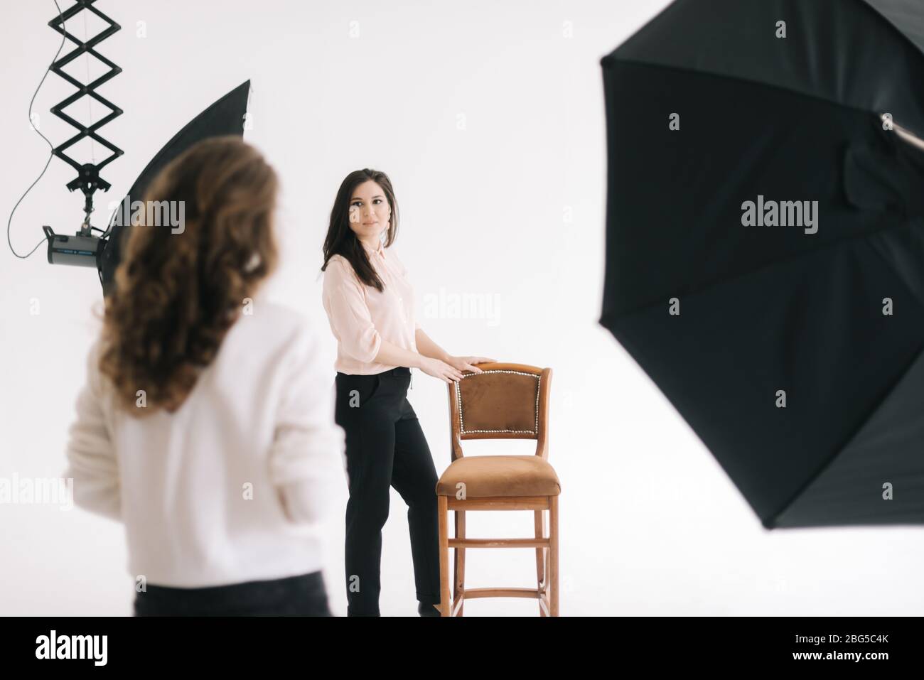 Young woman model posing with chair in photo studio for female ...