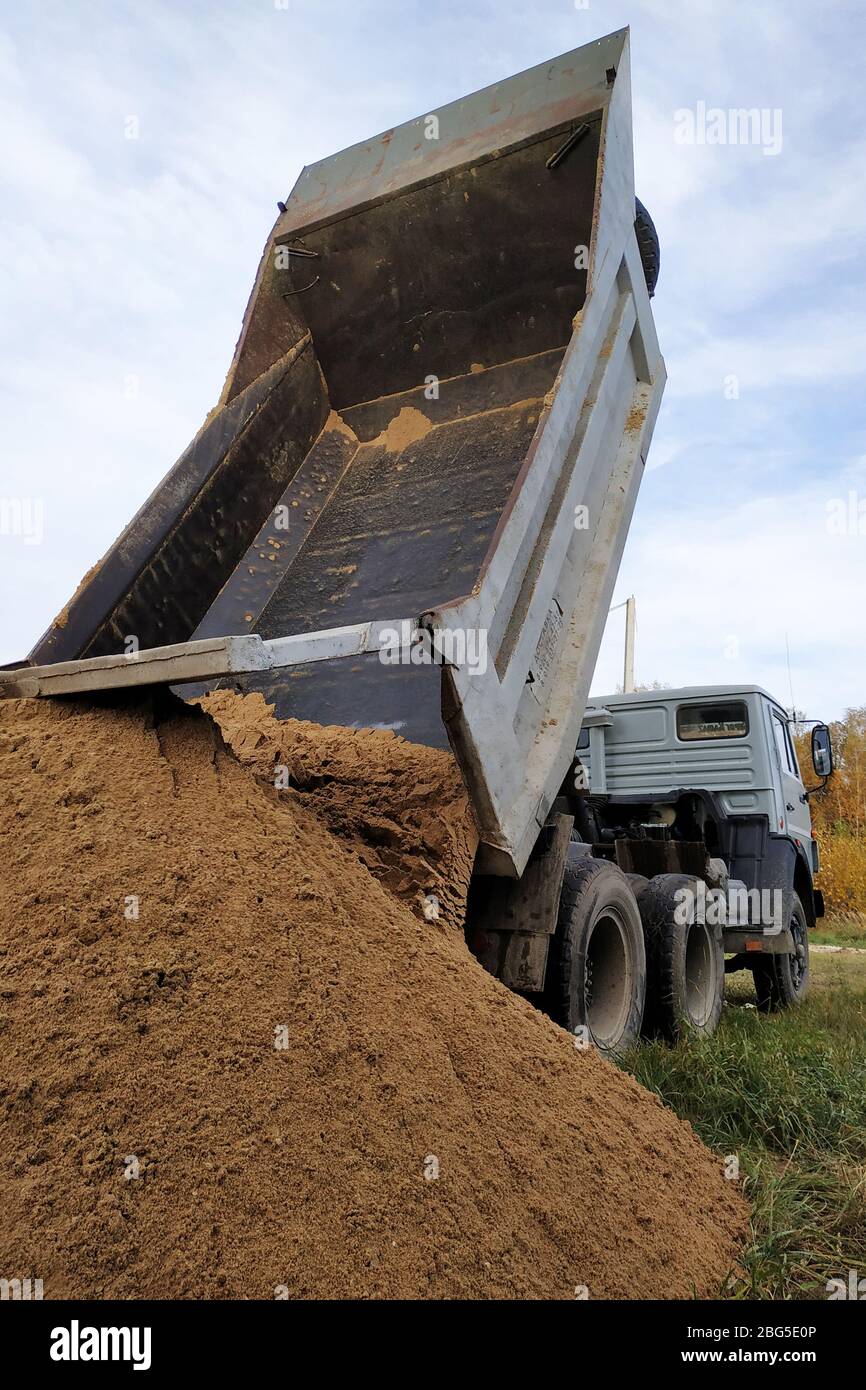 A dump truck unloads sand at a construction site to mix cement.2020 ...