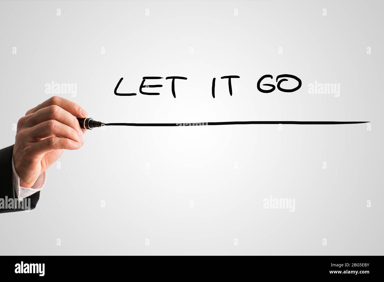 Man writing the words - Let it go - with a black marker pen from behind ...