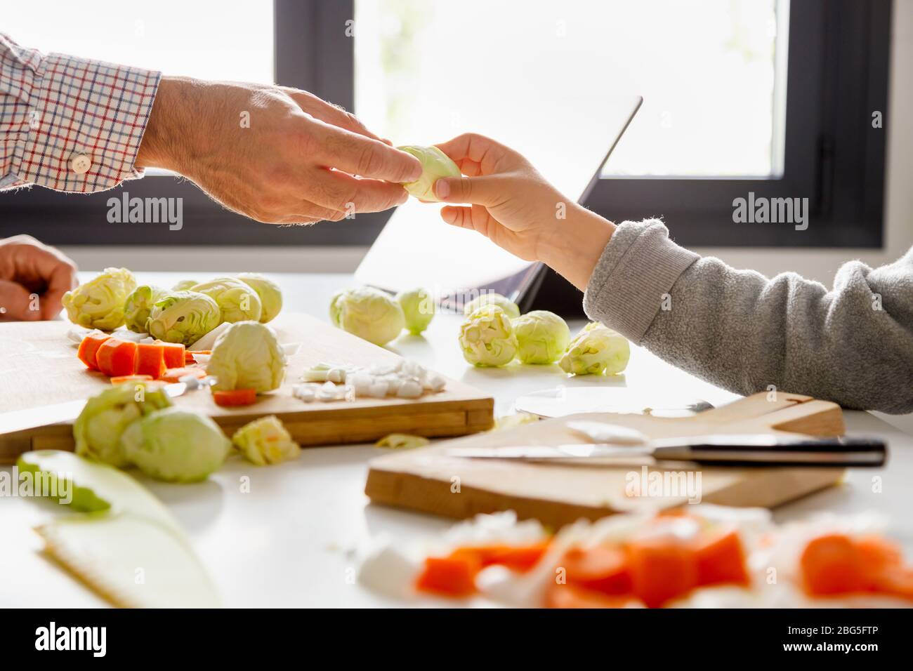 Hnad of a father giving his daughter a brussels sprout while cooking ...