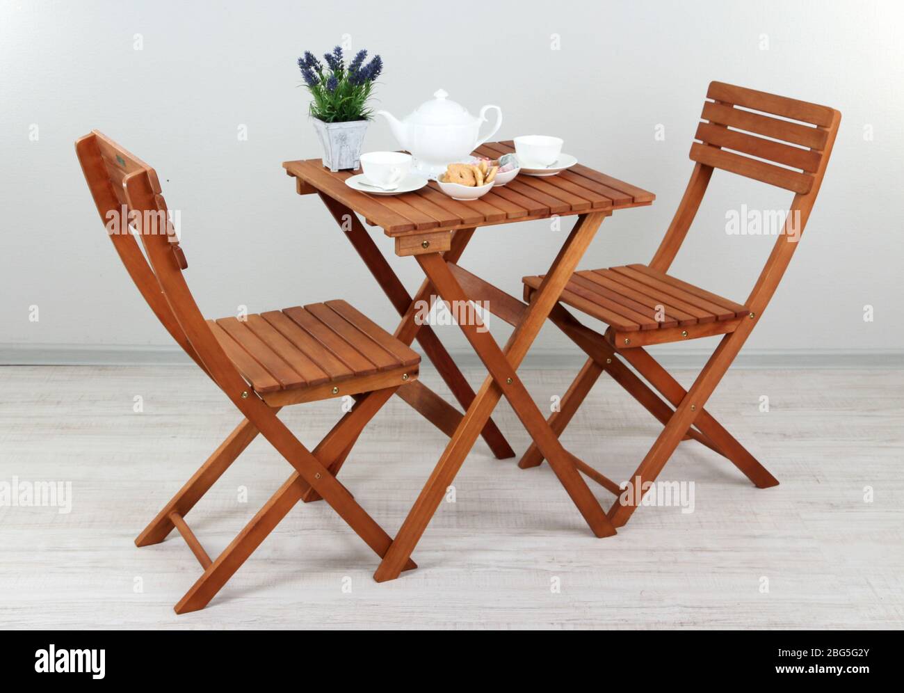 Wooden table with tea table setting in room Stock Photo - Alamy
