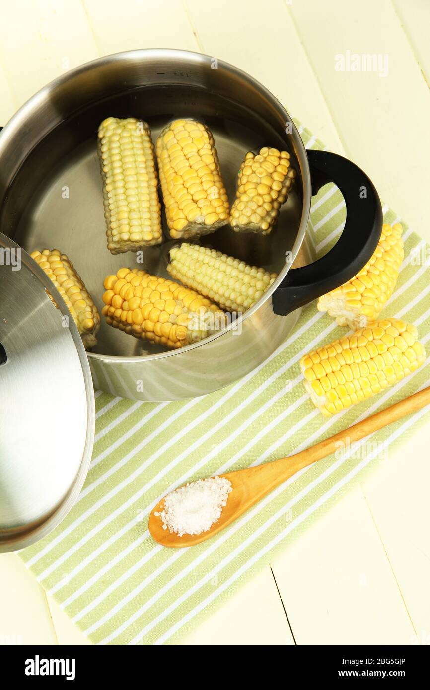 Boiled corn in pan, on wooden table, on wooden background Stock Photo ...