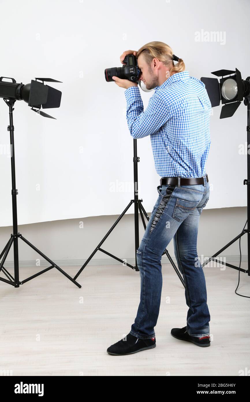 Handsome photographer with camera at working, on photo studio ...