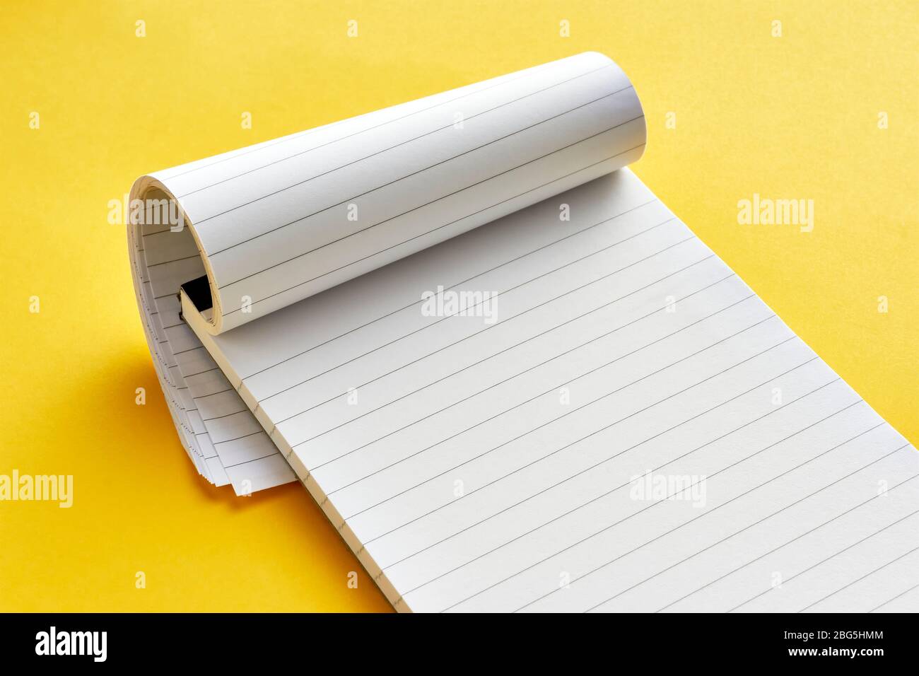 Top view of blank open notebook page with lines and on yellow ...